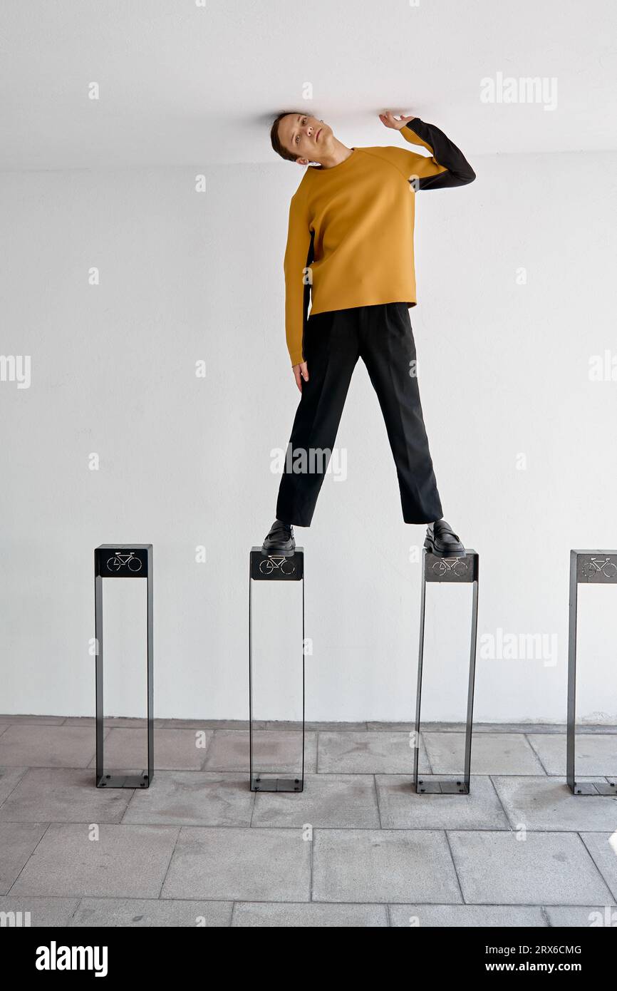 Man standing on bicycle rack and touching ceiling inside building Stock ...