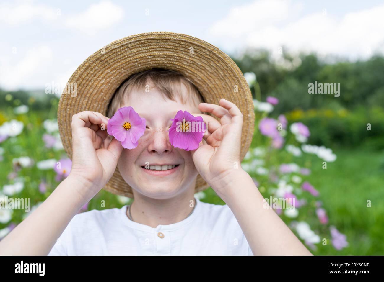 Happy boy holding pink flowers over eyes in garden Stock Photo - Alamy