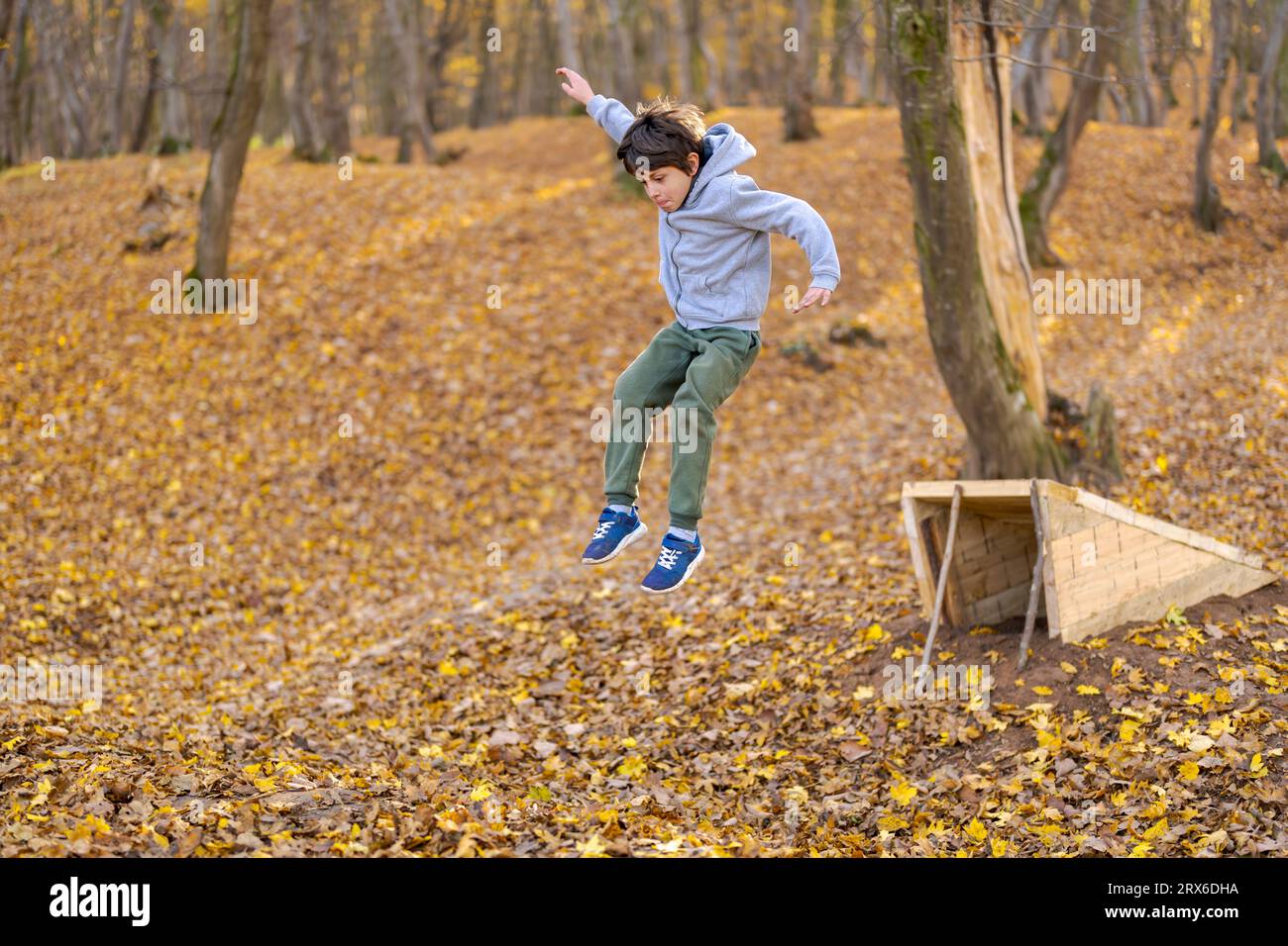 Cute boy playing and jumping in forest Stock Photo - Alamy