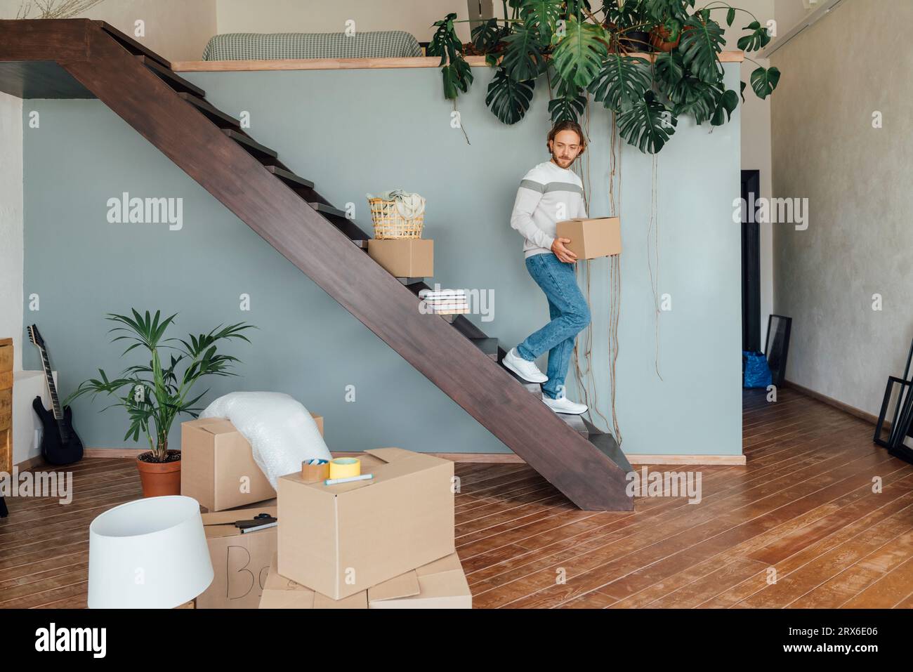 Young man moving down with cardboard box on staircase Stock Photo - Alamy