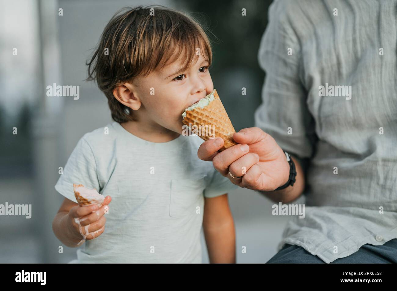Father feeding ice cream cone to son Stock Photo - Alamy