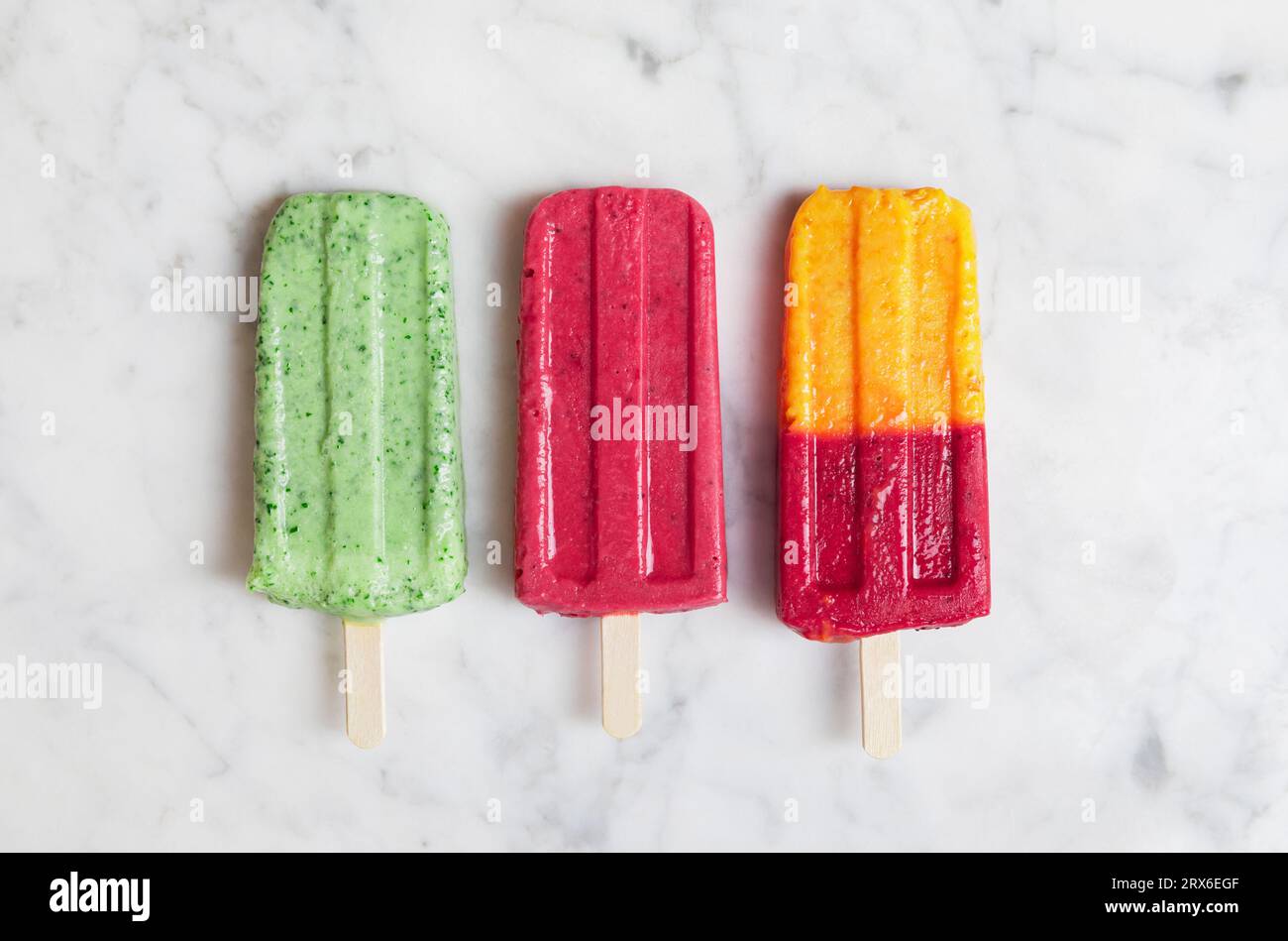Homemade berry fruit popsicles flat laid against marble background ...