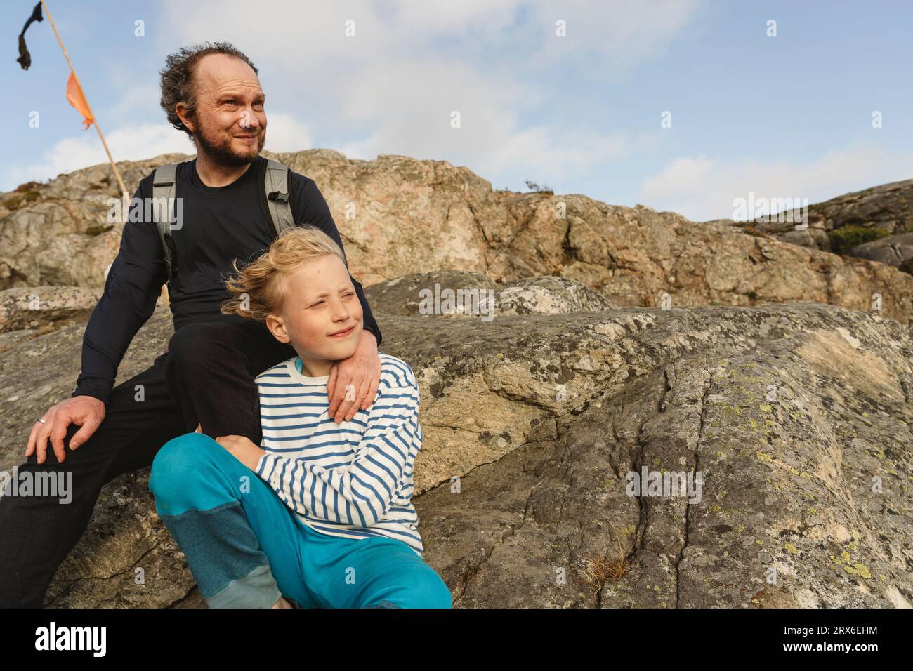 Thoughtful father and son sitting together on rock Stock Photo - Alamy