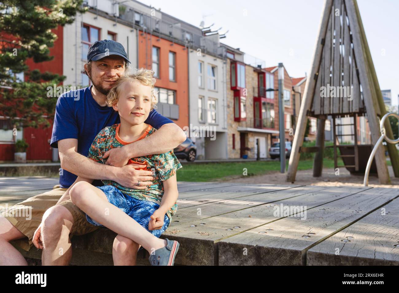 Thoughtful father hugging son sitting on playground Stock Photo - Alamy