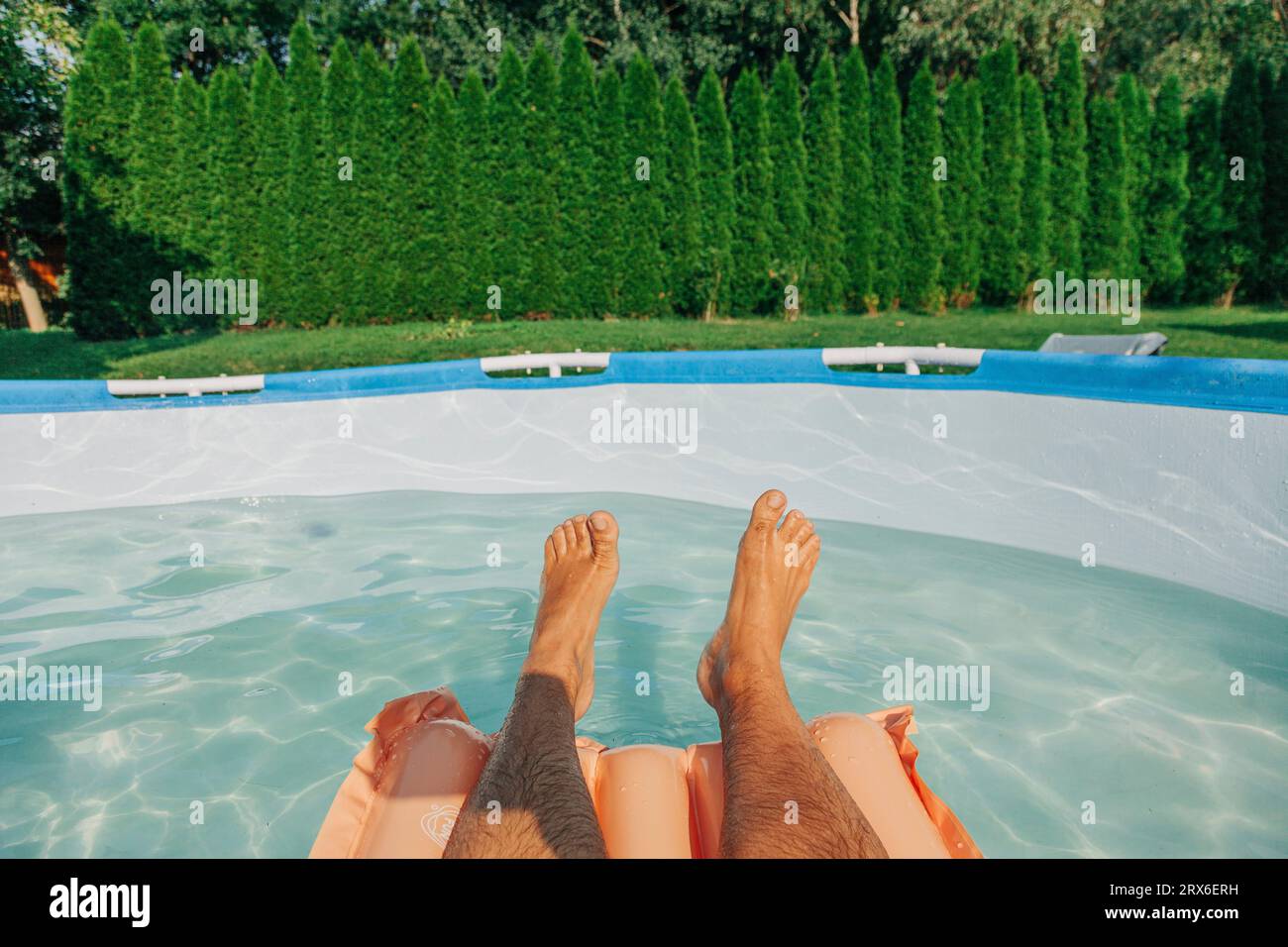 Legs of man floating in wading swimming pool at backyard Stock Photo ...