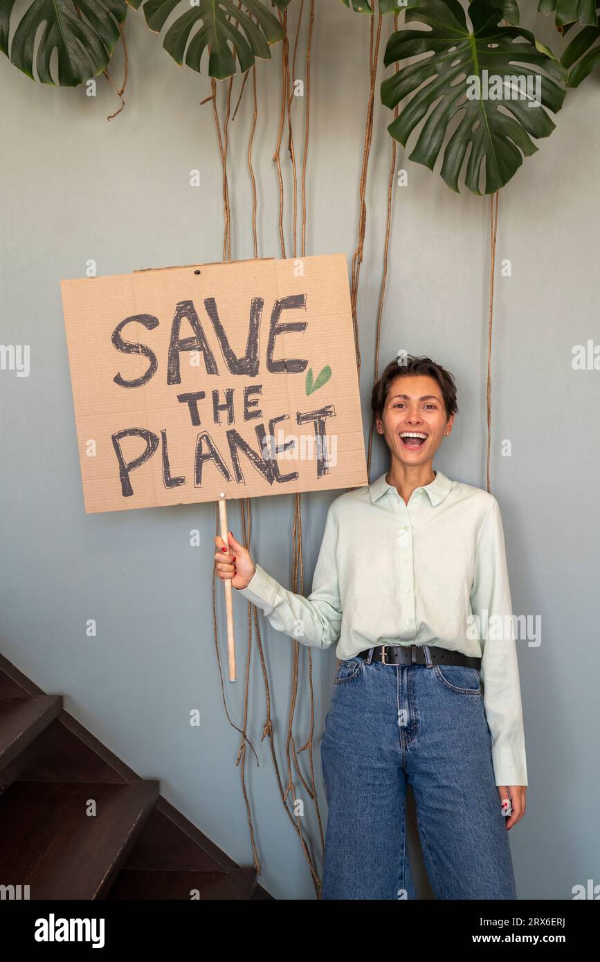Happy activist standing with placard in front of wall at home Stock ...