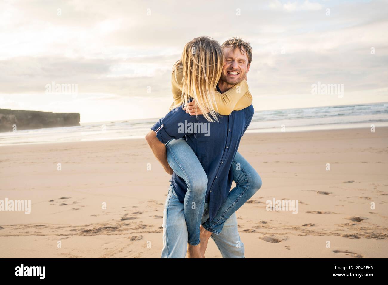 Happy man giving piggyback ride to woman at beach Stock Photo - Alamy