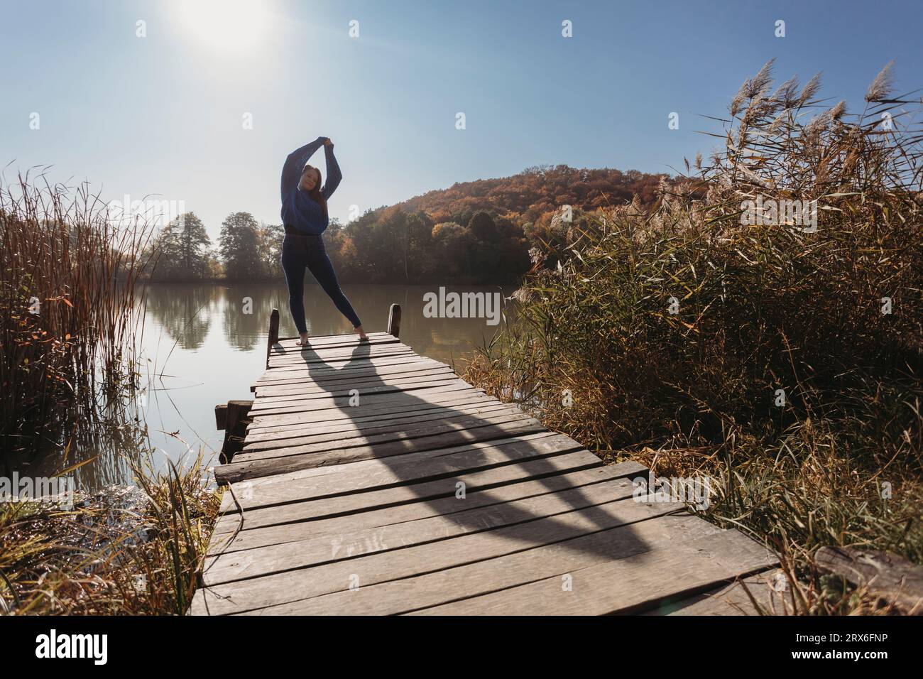 Woman standing with arms raised on jetty near lake Stock Photo - Alamy
