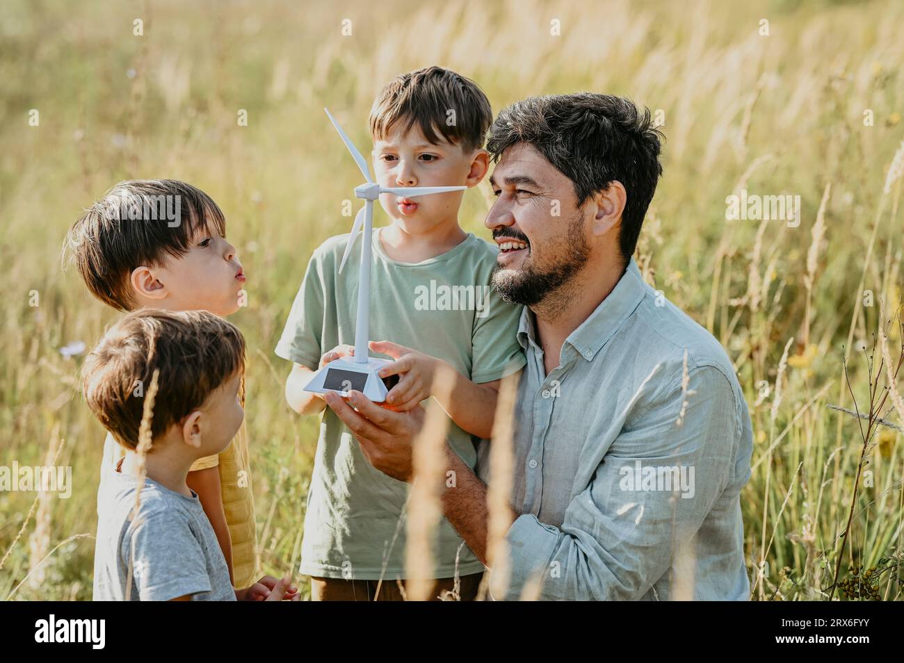 Boys blowing on wind turbine model in field Stock Photo - Alamy