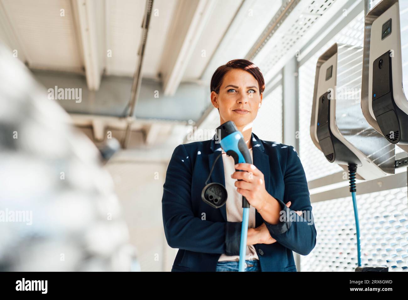Confident businesswoman with electric plug at charging station Stock ...