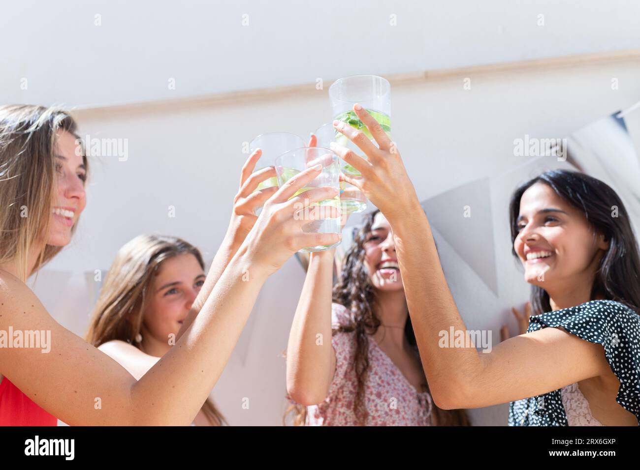 Smiling friends raising toast in front of wall Stock Photo - Alamy