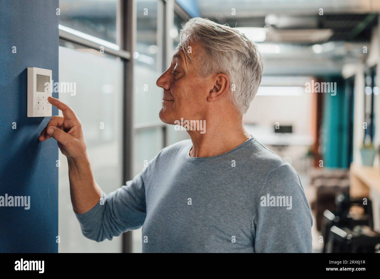 Smiling senior businessman using digital thermostat at work place Stock ...