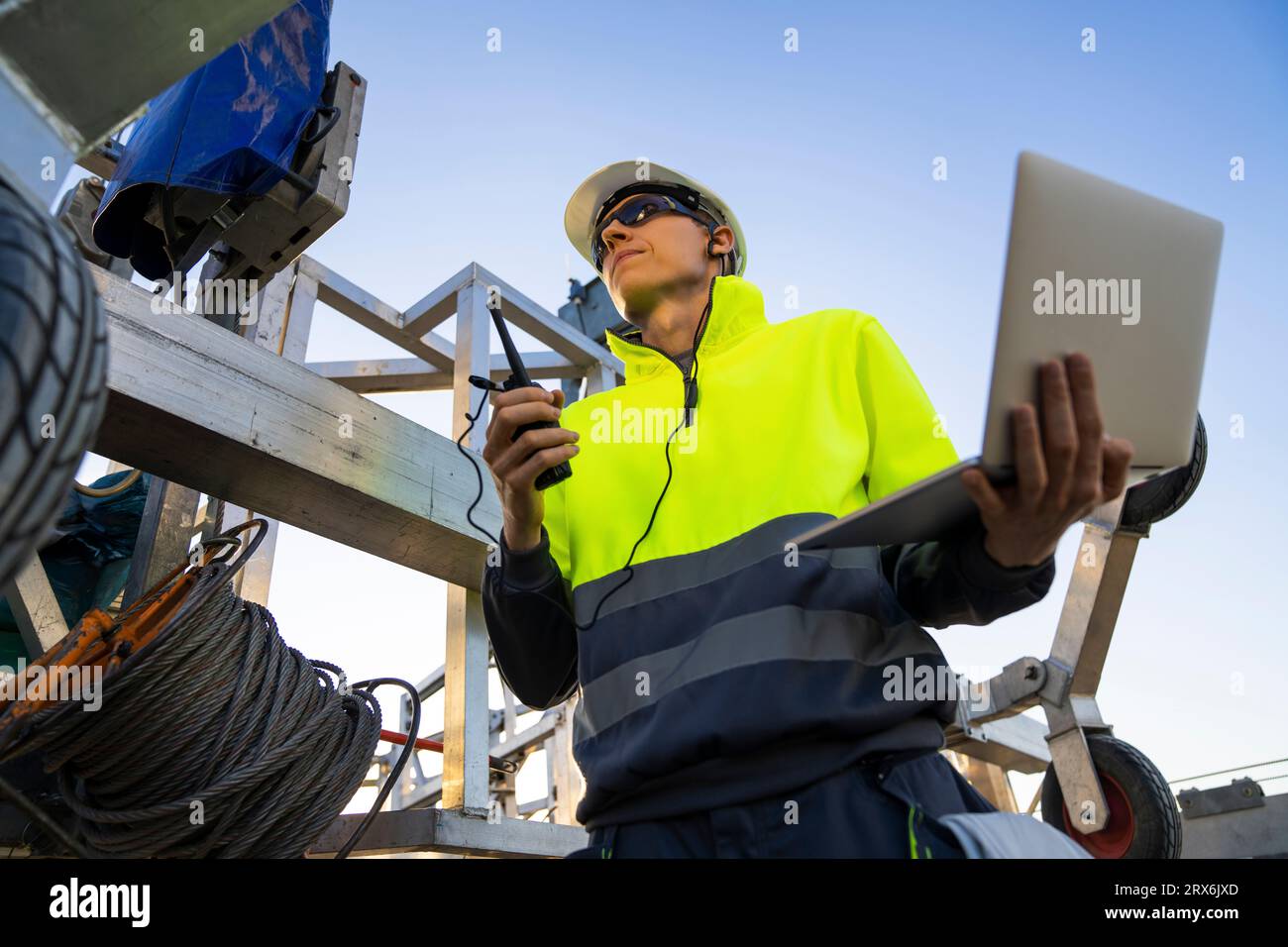 Engineer with laptop and walkie-talkie by wind turbine maintenance ...