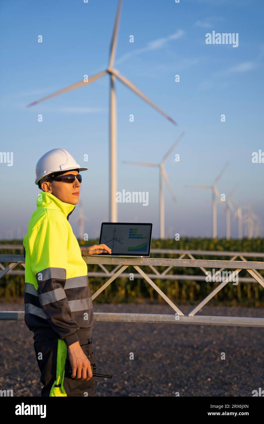 Engineer with laptop by wind turbine field Stock Photo - Alamy