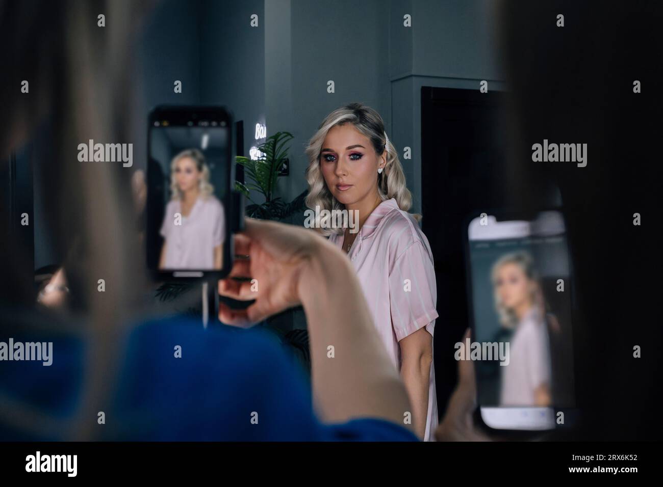 Make-up artist photographing client with smart phone in salon Stock ...