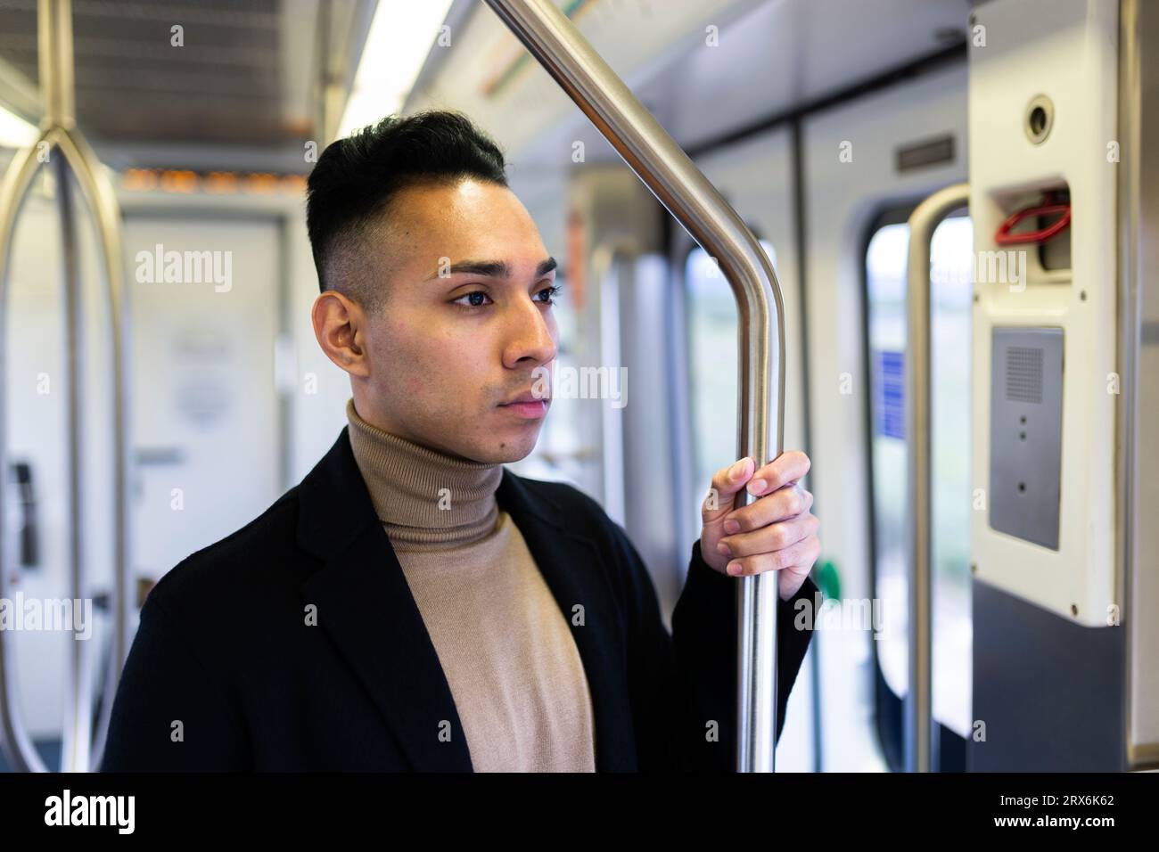 Contemplative man standing in train Stock Photo - Alamy