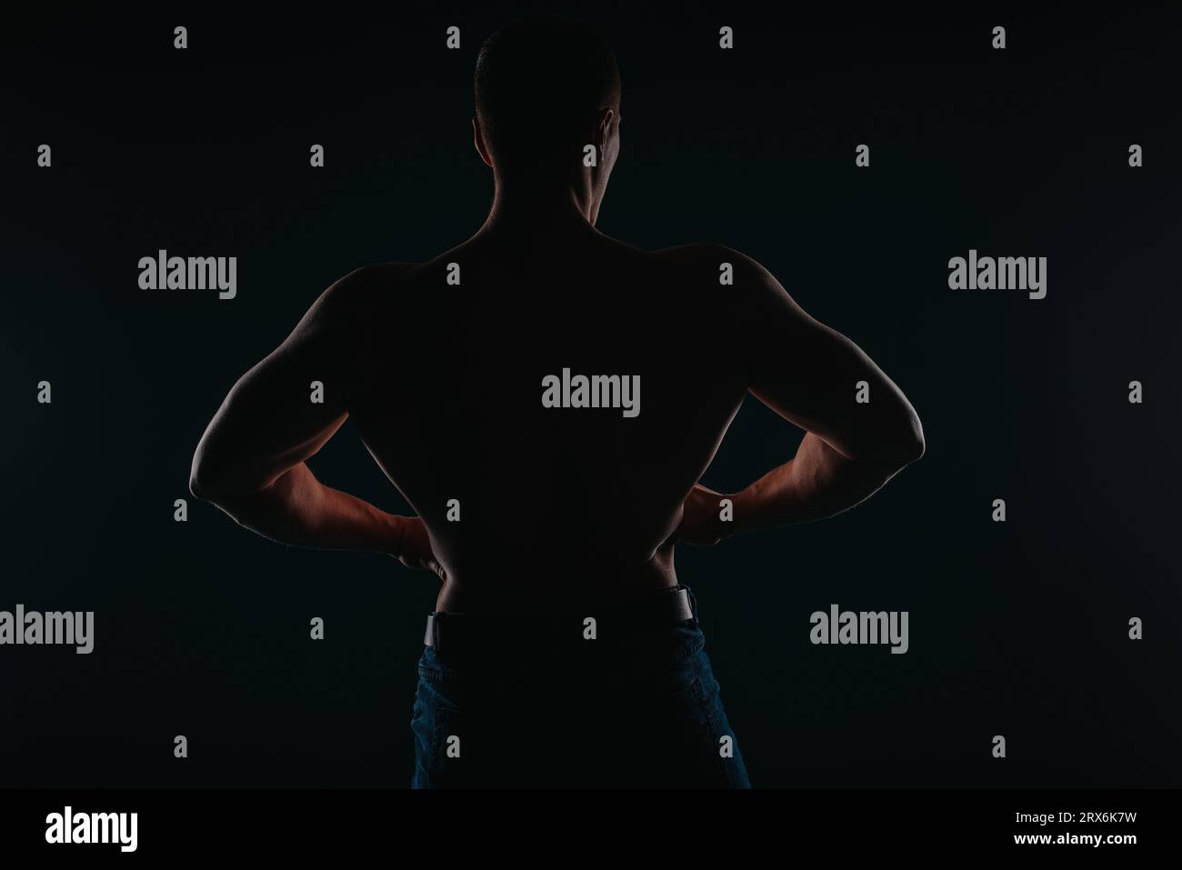 Well-built and charming man standing in front of a dark background and ...
