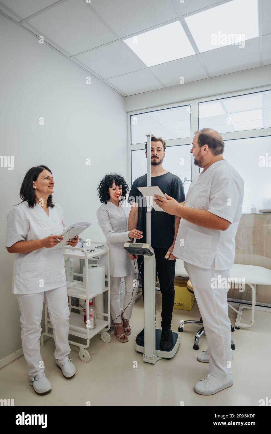 Team of medical professionals measuring patient height. He did not ...