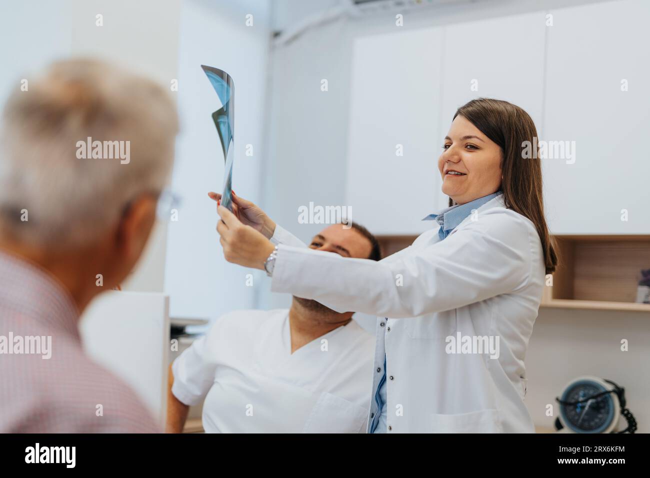 Doctors reviewing x-ray results in her office, analyzing the patient's ...