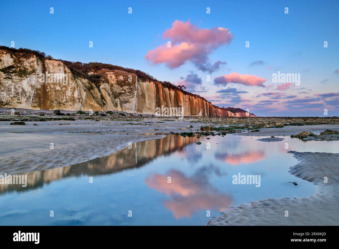 Reflection of chalk cliffs and cloudy sky in water puddle at beach ...