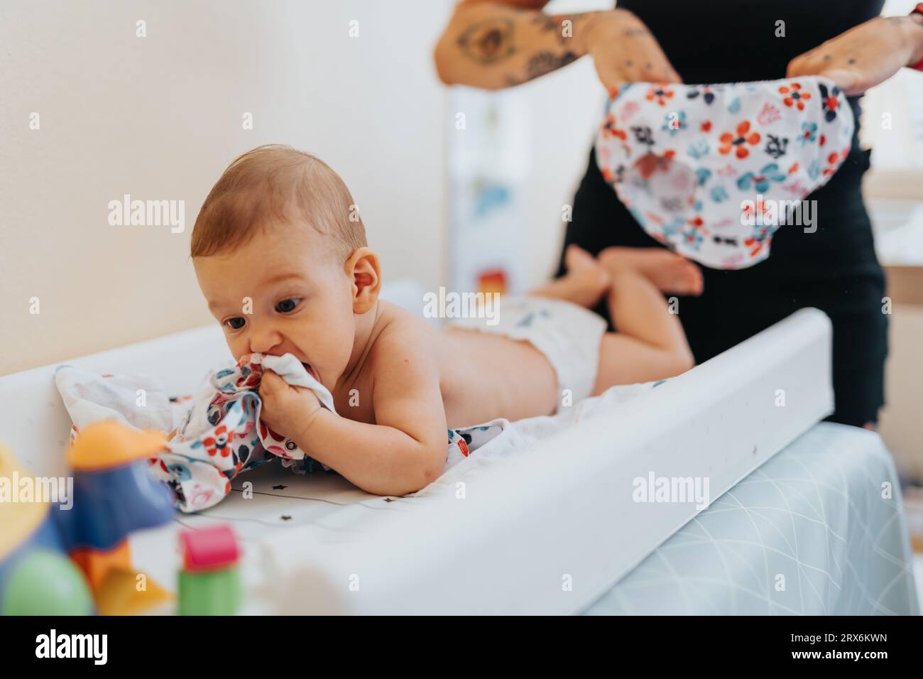 Mother changing her little baby daughter diaper. Baby playing with ...