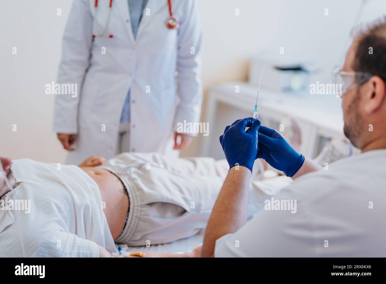 A doctor examines a patient receiving infusion therapy in a hospital ...