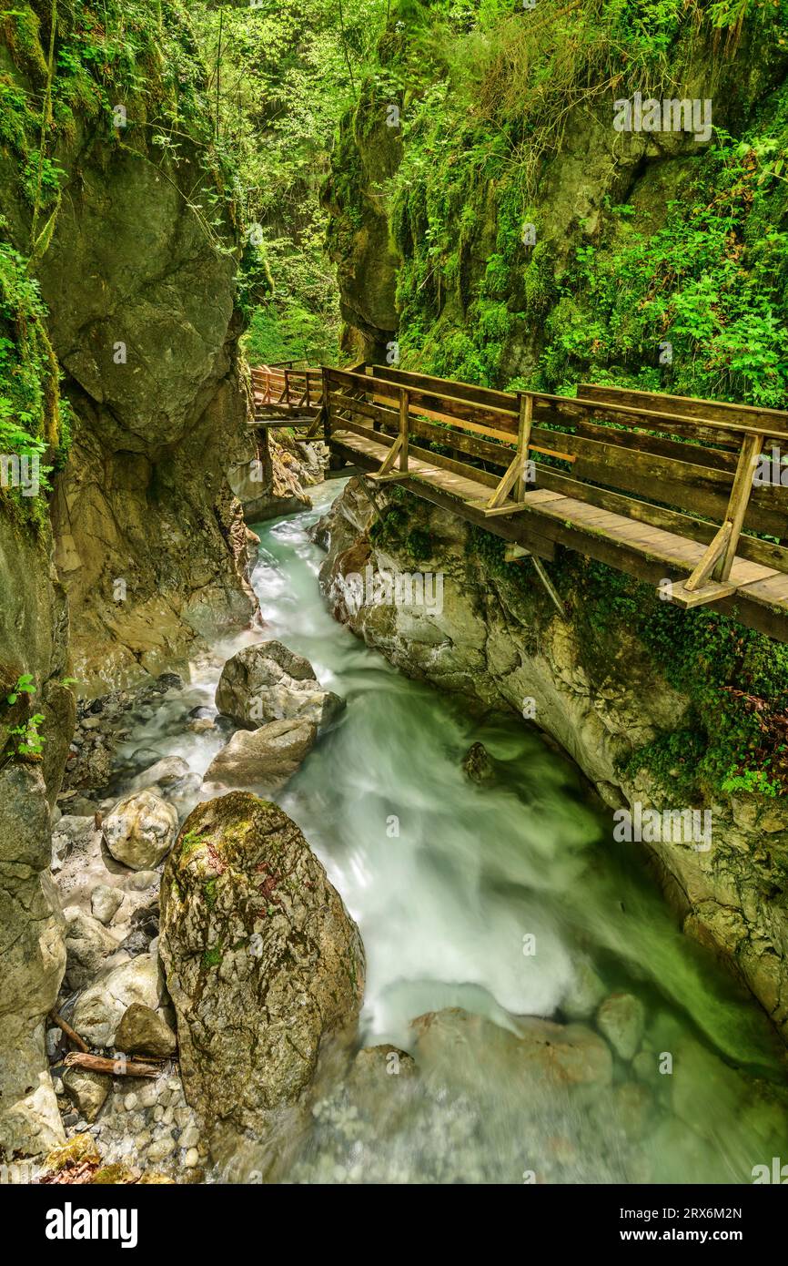 Wooden narrow bridge over water with rocky mountains Stock Photo - Alamy