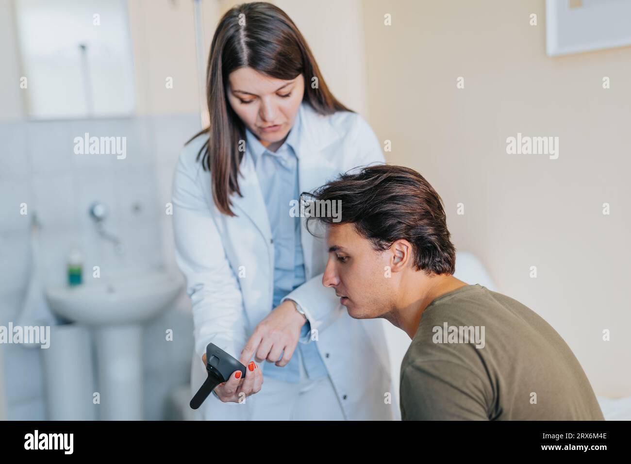 A physician in a clinic checks eyes, ears, and throat of a young ...