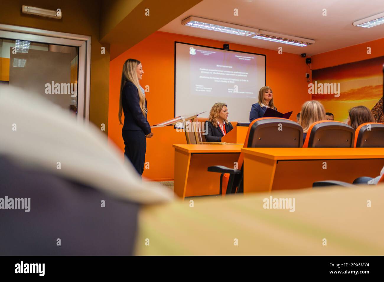 Adult female university professor sitting at the desk and giving a ...