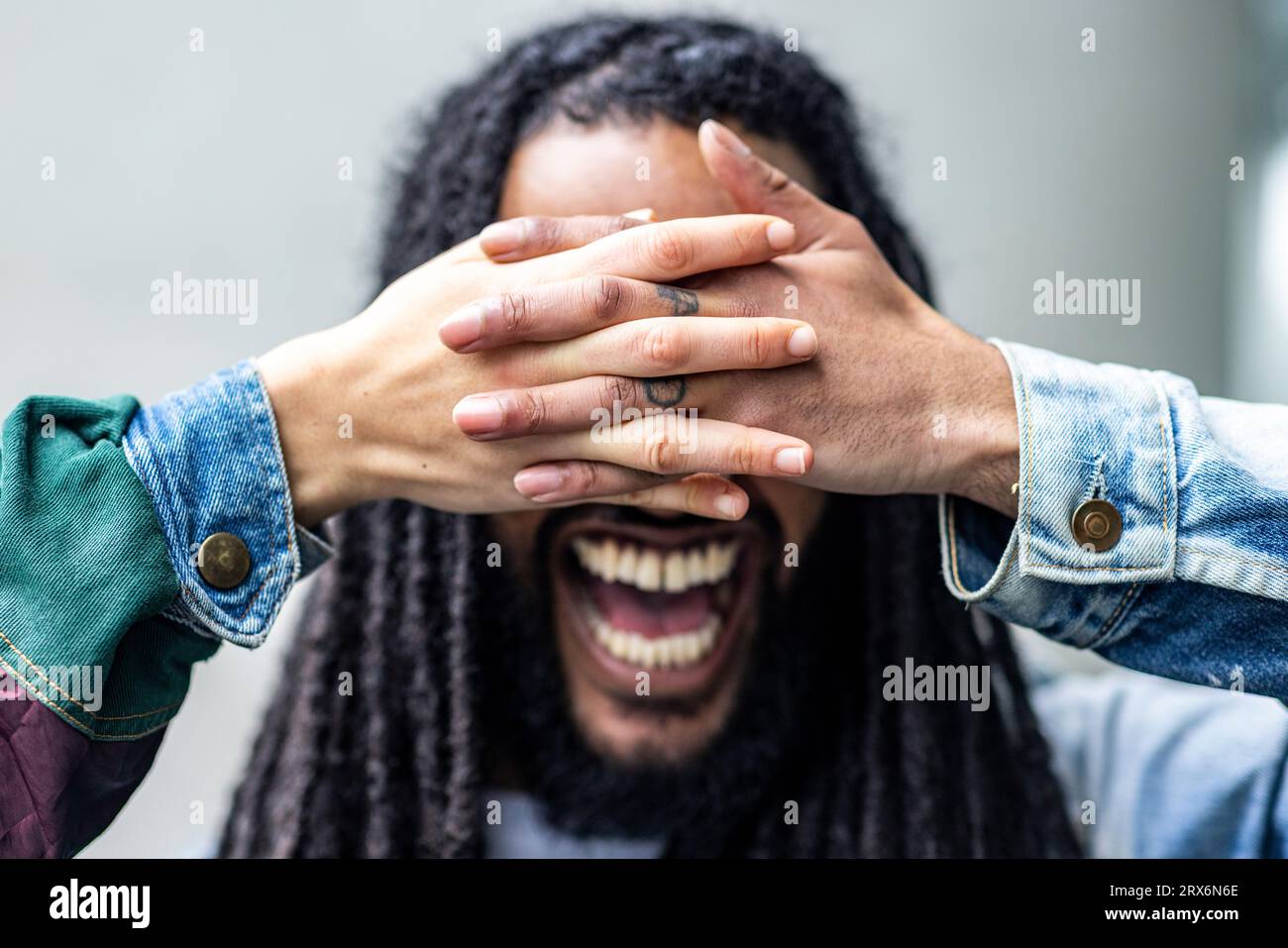Cheerful man holding hands over face with woman Stock Photo - Alamy