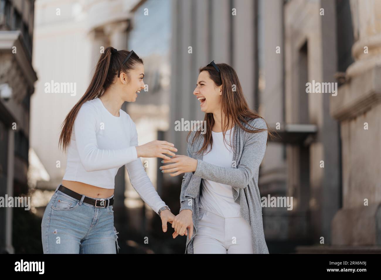 Two women standing next to each other in front of a building Stock ...