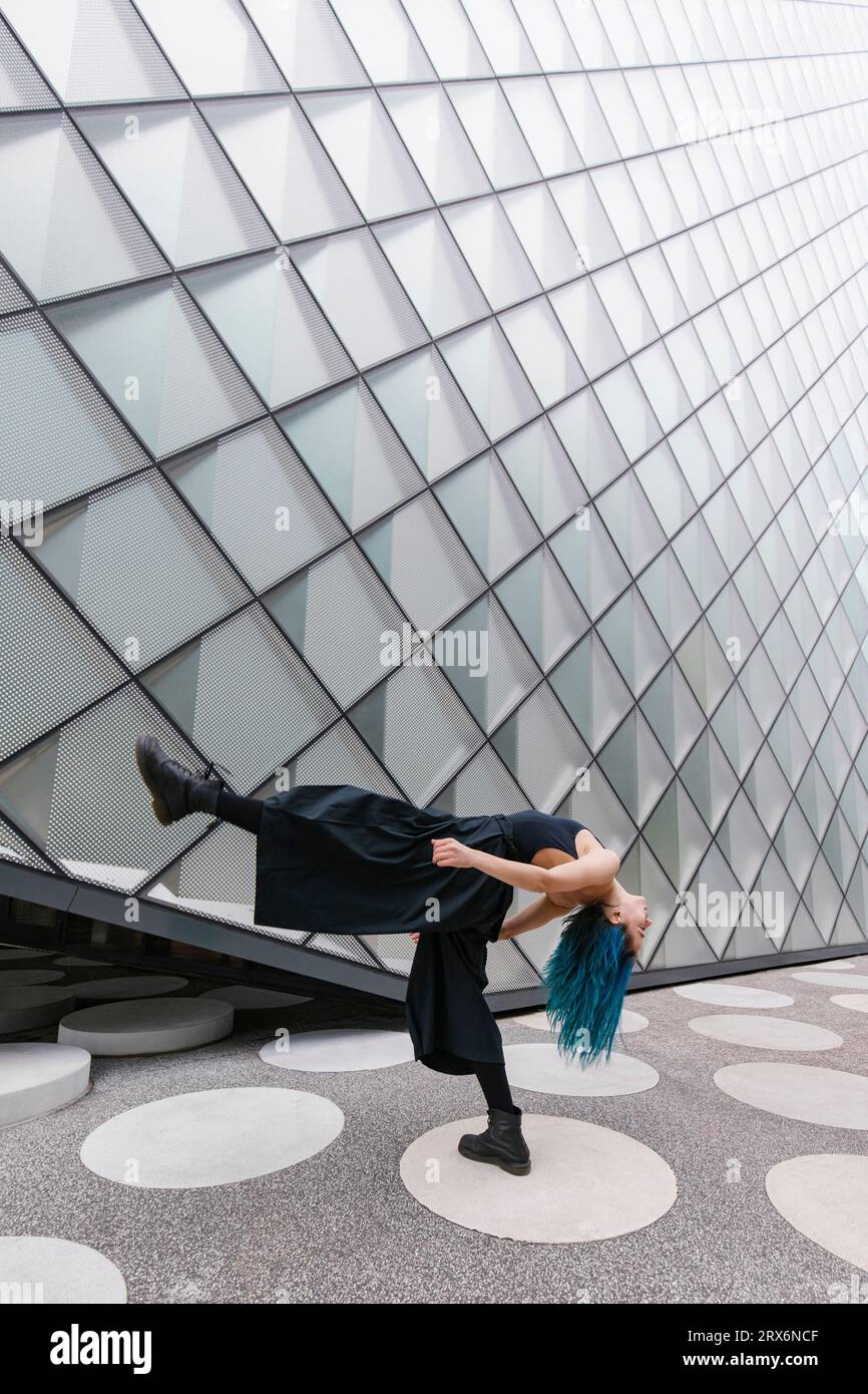 Flexible young dancer bending over backwards in front of modern ...