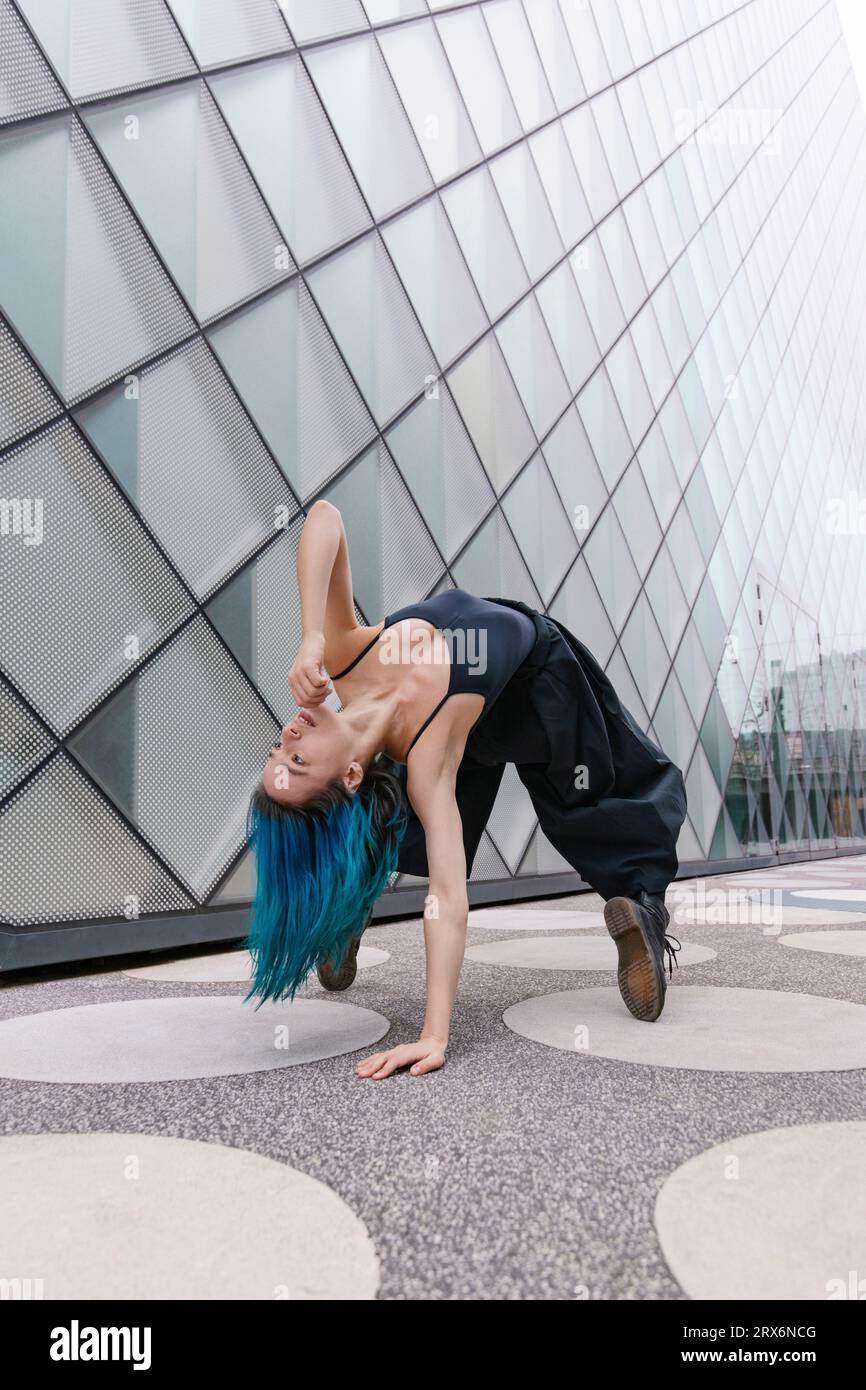 Flexible dancer bending over backwards in front of modern building ...