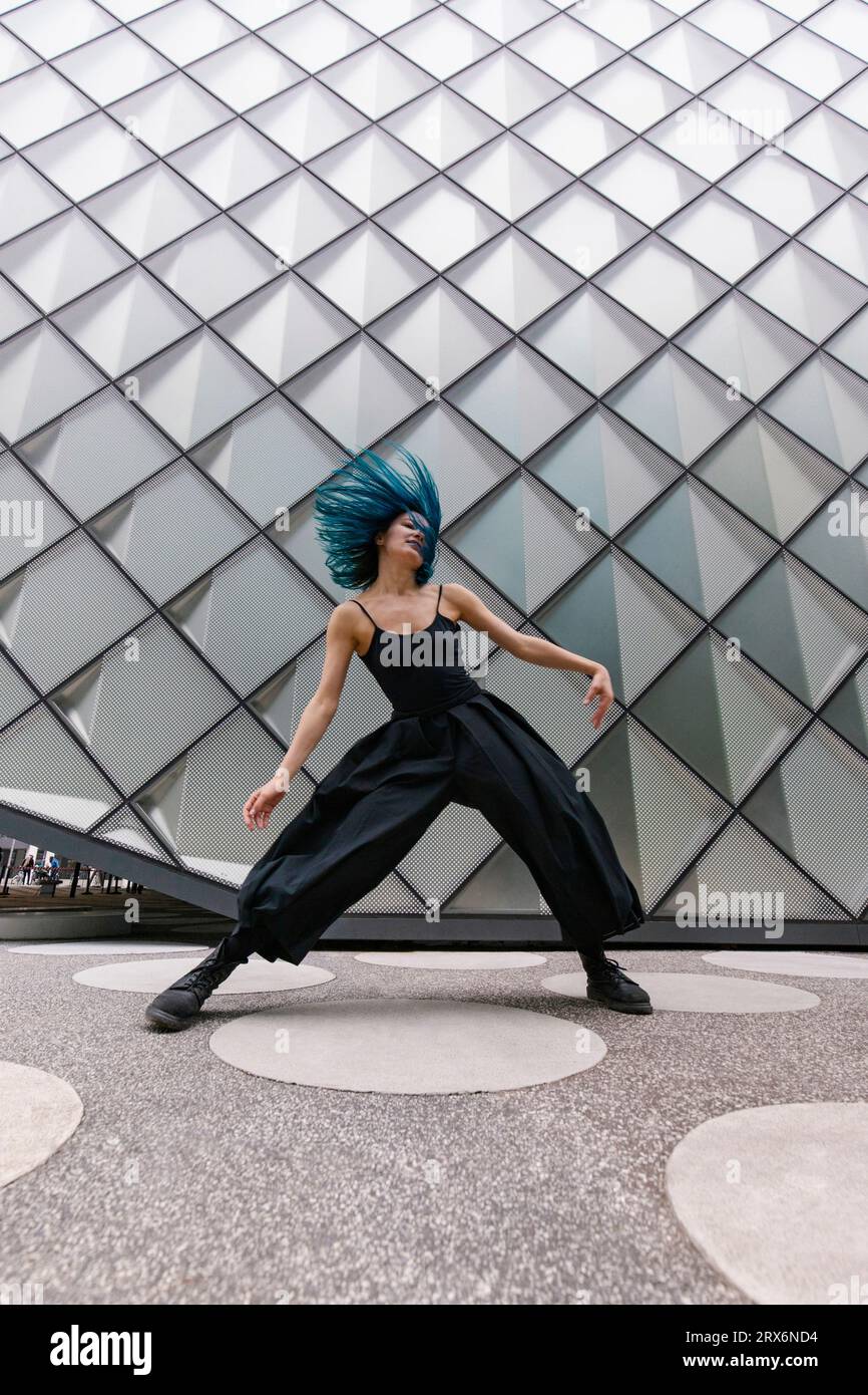 Dancer with dyed blue hair dancing near modern building Stock Photo - Alamy