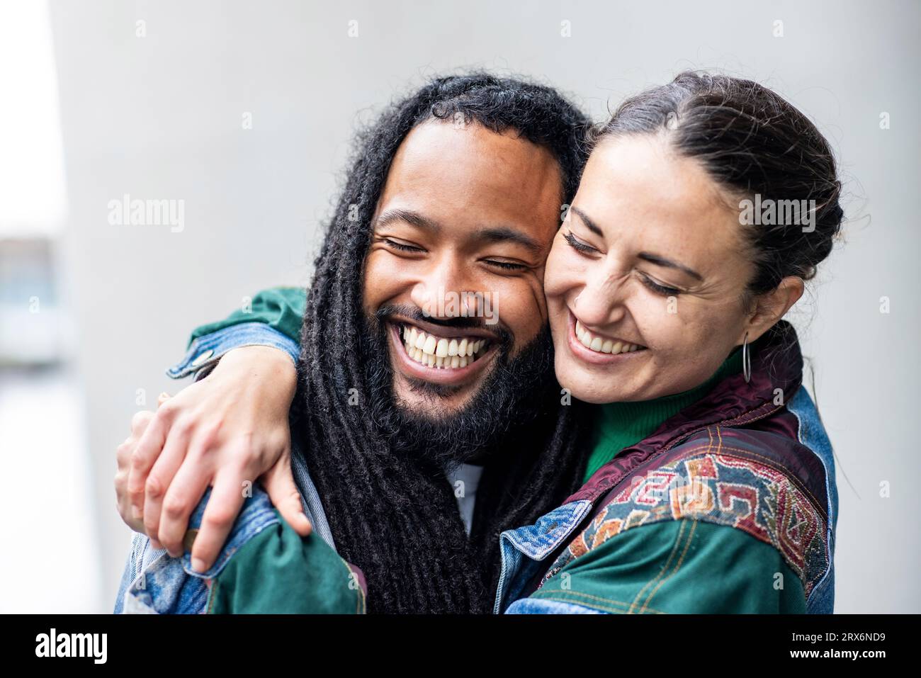 Happy multiracial couple hugging in front of wall Stock Photo - Alamy