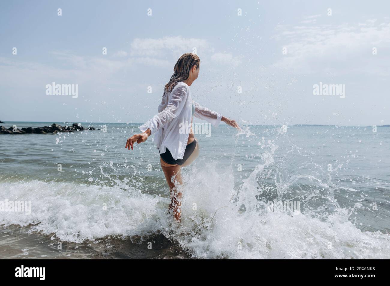 Playful woman splashing water at beach Stock Photo - Alamy