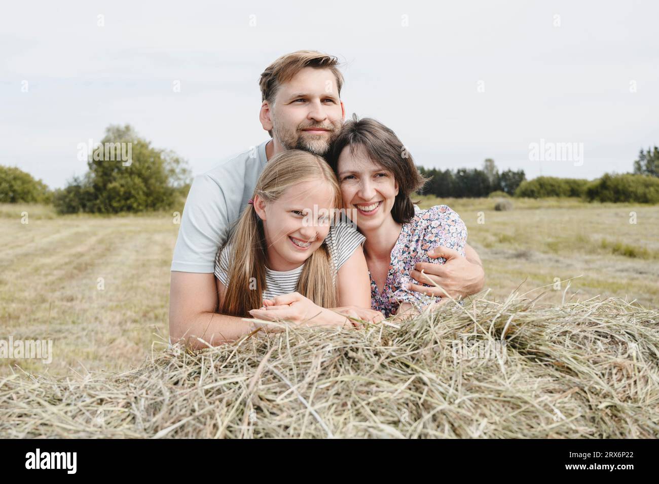 Happy family leaning on hay in field Stock Photo - Alamy