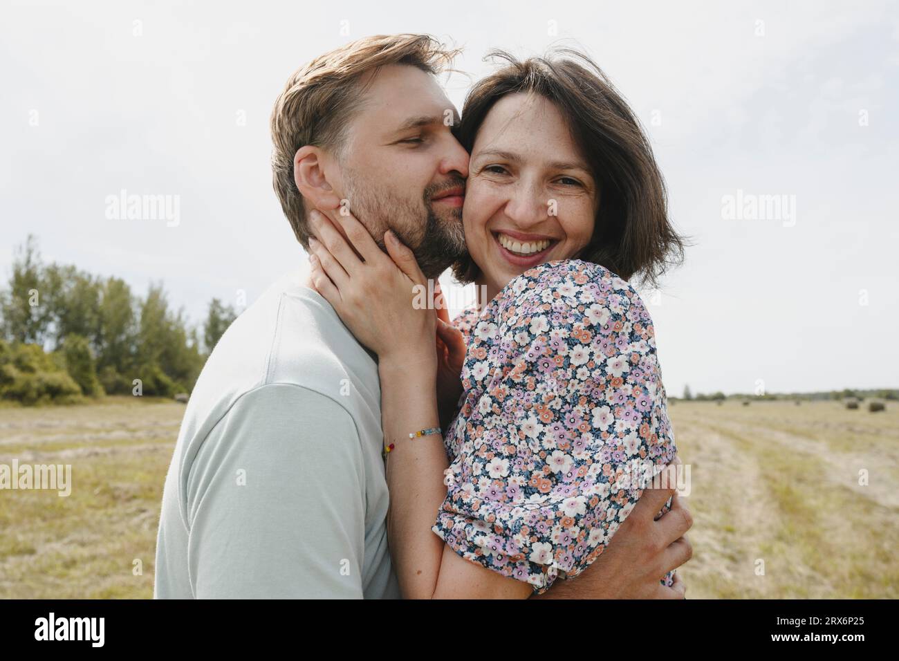 Smiling man hugging and embracing woman in field Stock Photo - Alamy