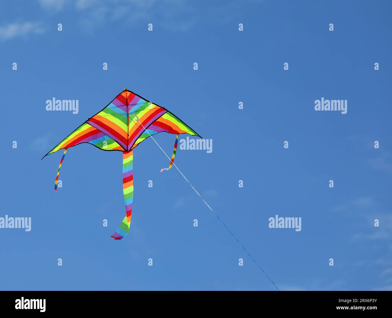 colorful kite of many colors of the rainbow flies tied to a thread in ...