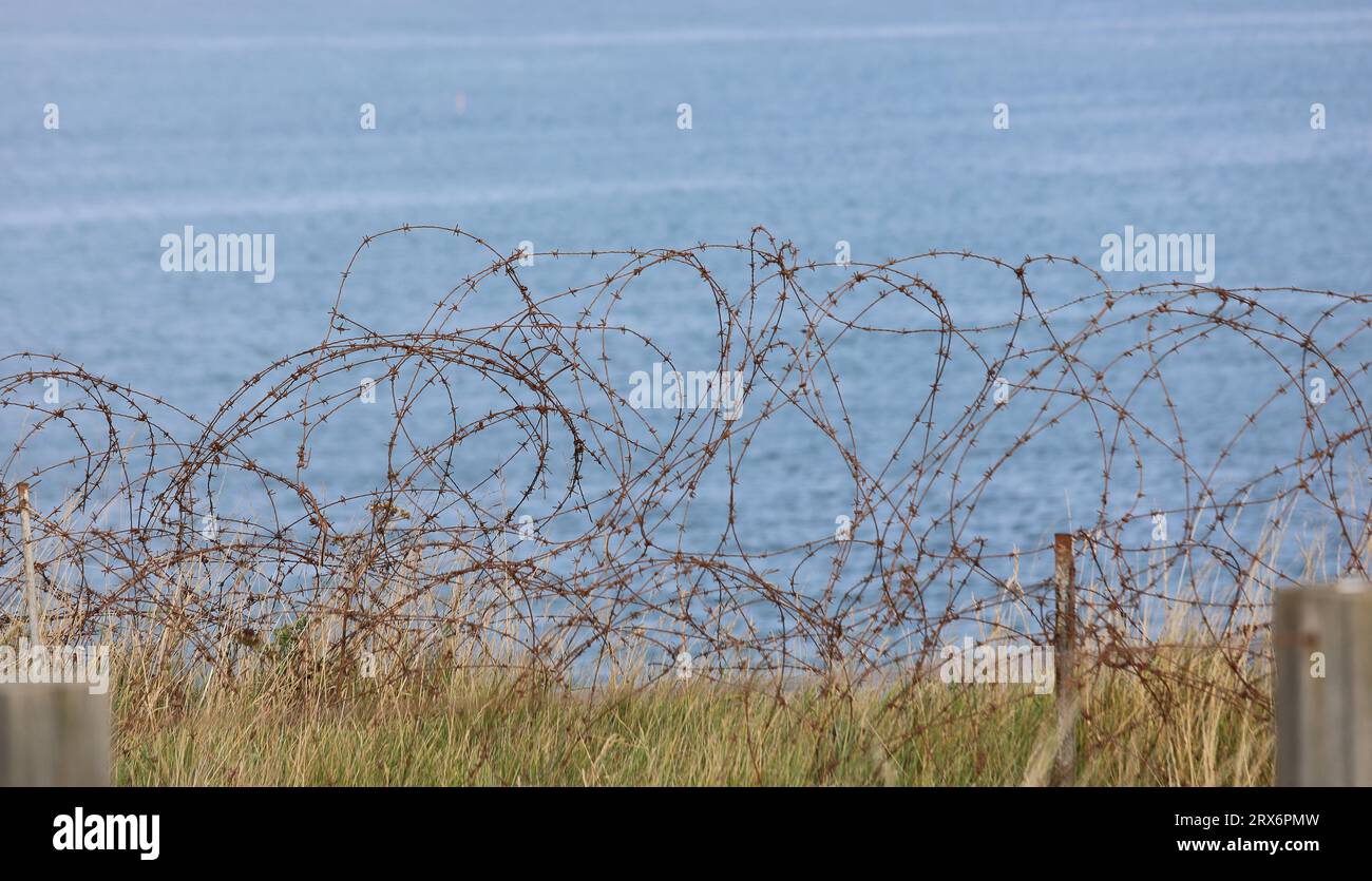 barbed wire over the hill and in the background the sea without people ...