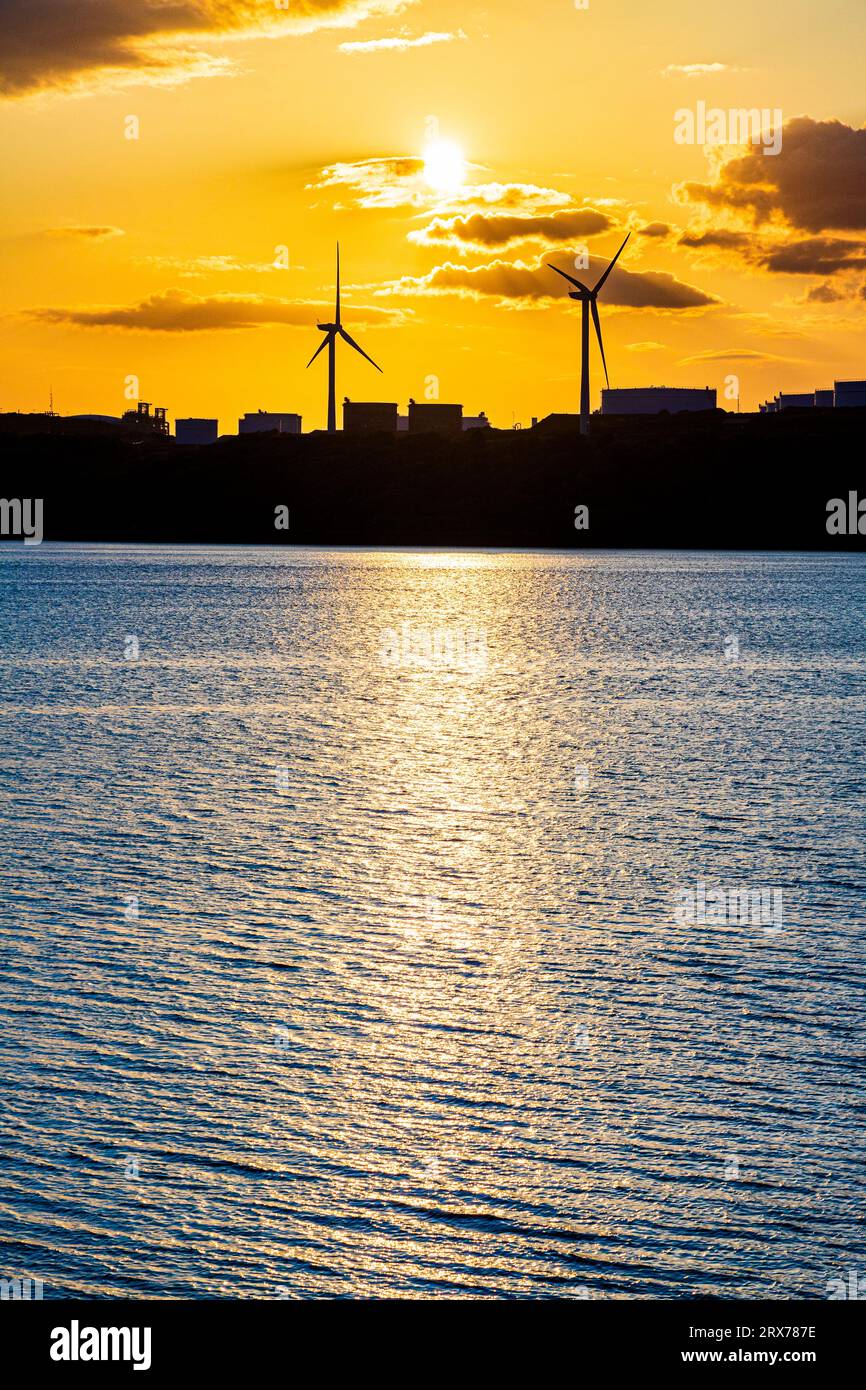 The sun setting behind wind turbines at the former Gulf oil refinery at ...