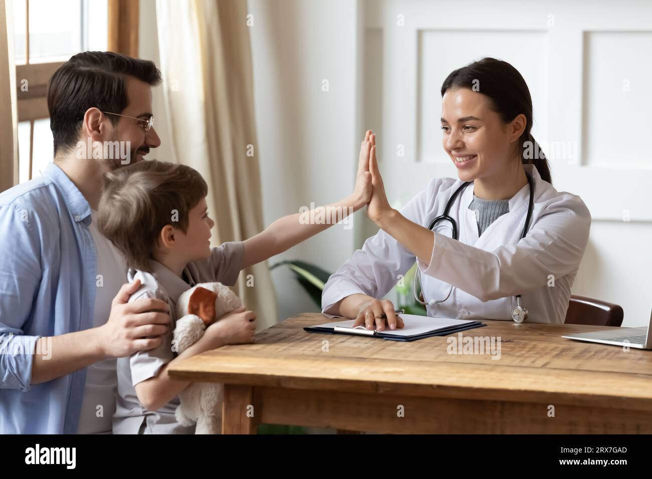 Smiling doctor greeting little patient with father at medical ...