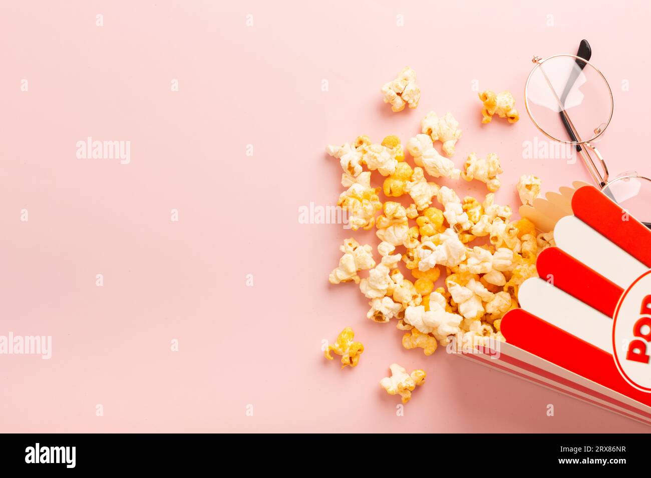 Popcorn is scattered over a pink background. Empty space for text. High ...