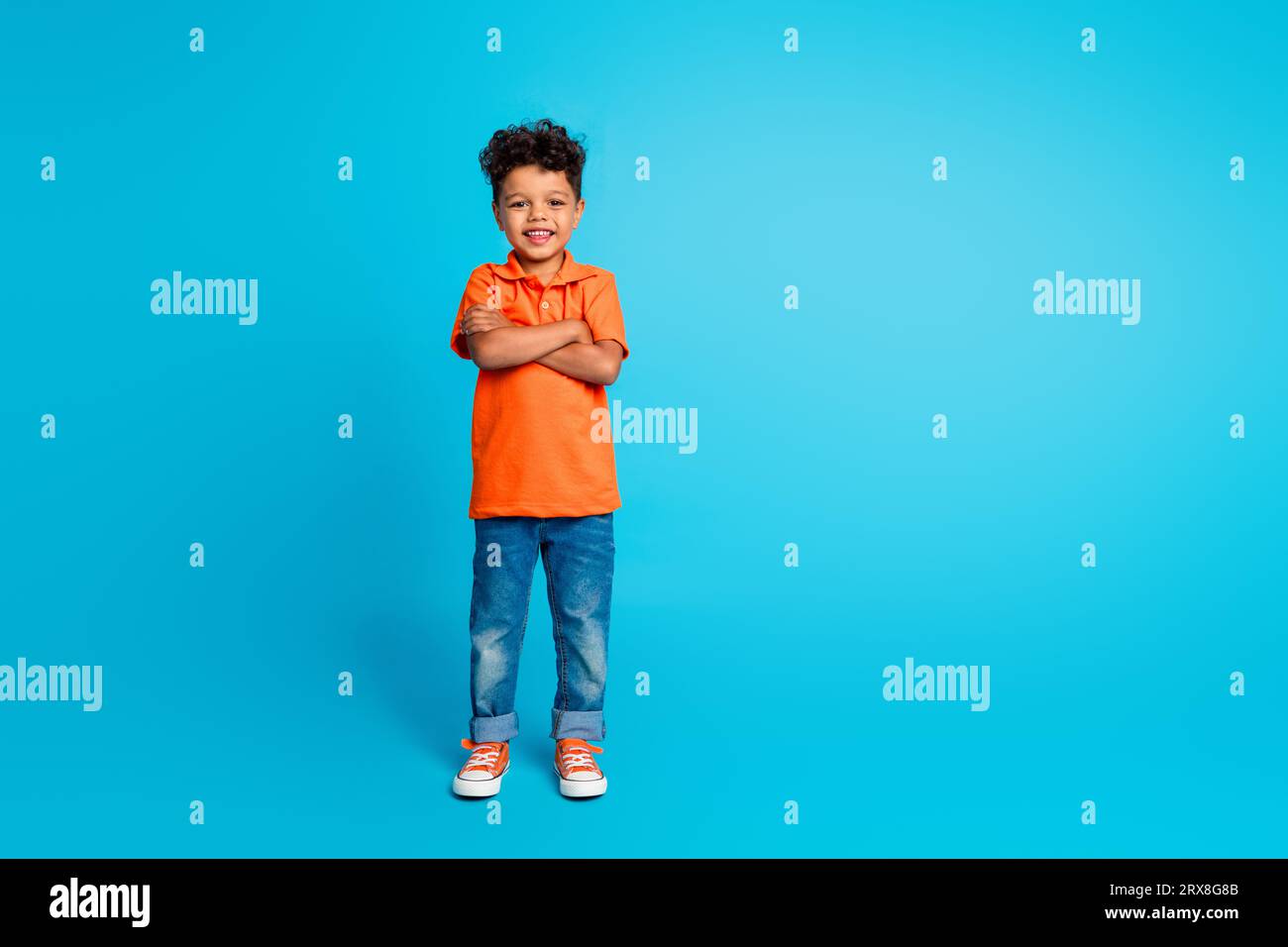 Photo of positive smart kid boy with folded arms isolated blue color ...