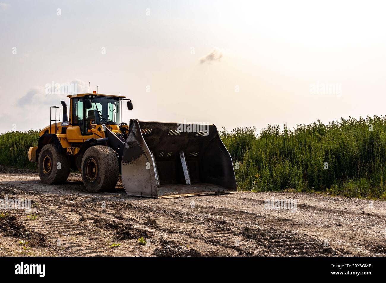 Yellow bulldozer - parked on dirt road - rural area with field and ...