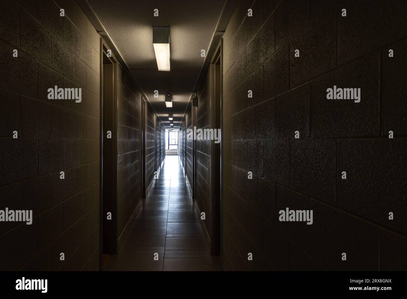 Dark and narrow hallway with industrial texture and single light source ...