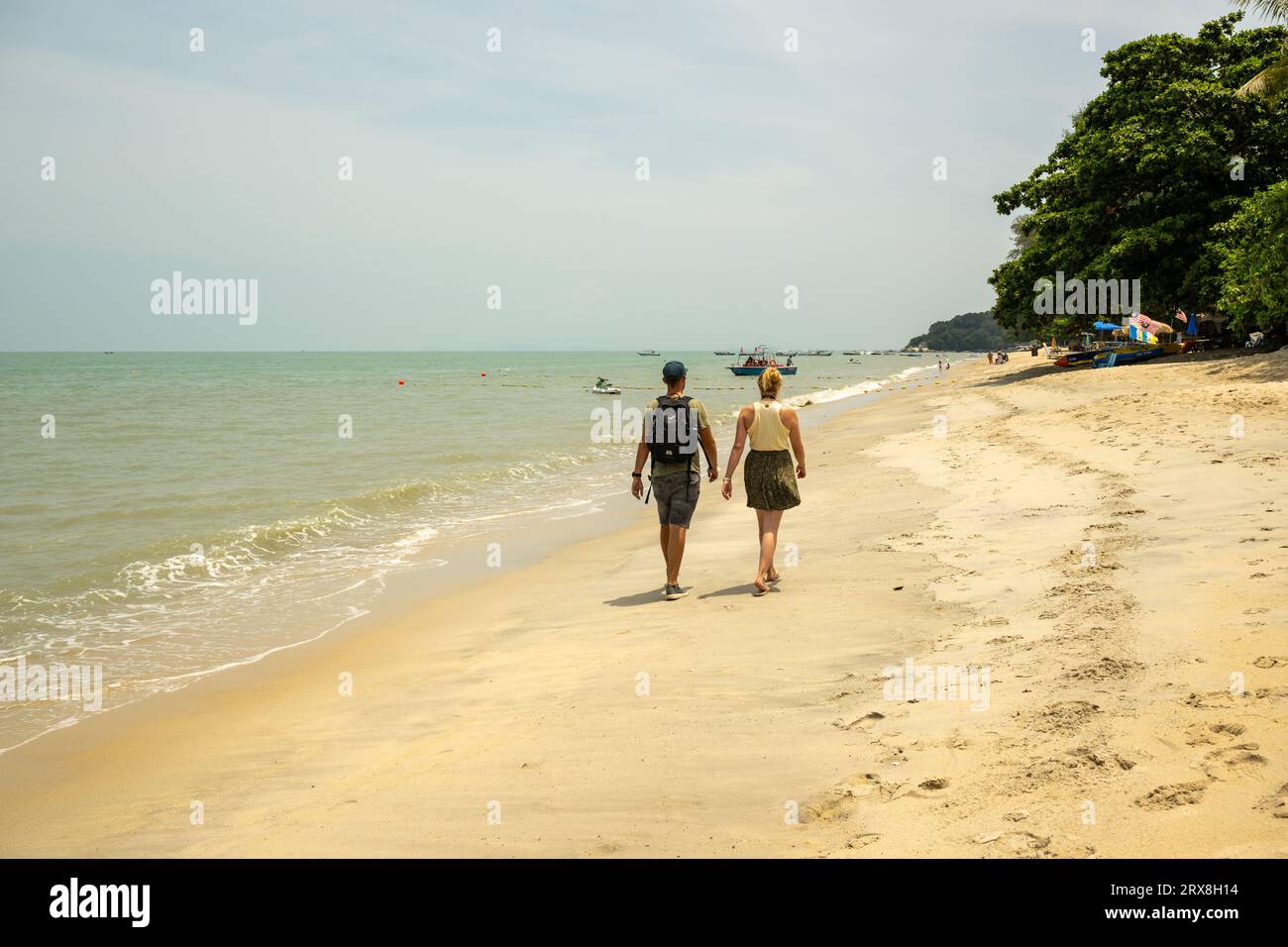 Couple walking along Batu Ferringhi Beach, Penang, Malaysia Stock Photo ...