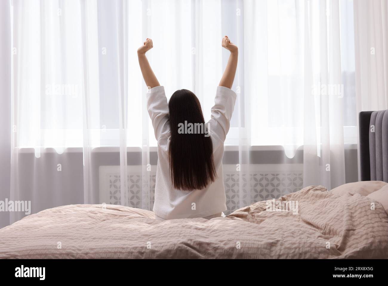 Woman stretching on bed at home, back view. Lazy morning Stock Photo ...