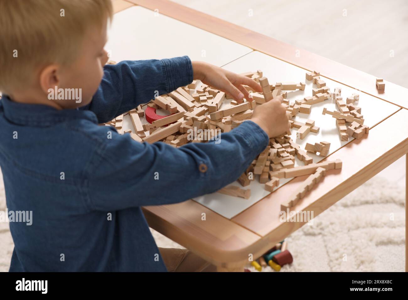 Little boy playing with wooden blocks at table indoors. Child's toy ...