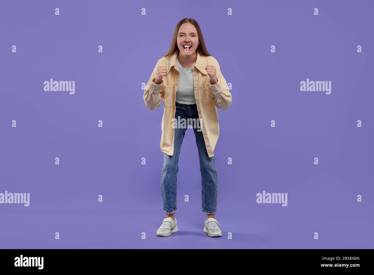 Emotional sports fan celebrating on purple background Stock Photo - Alamy
